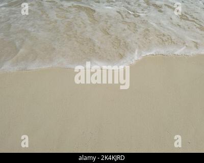 Waves racing towards the pristine white sand beach on a remote tropical ...