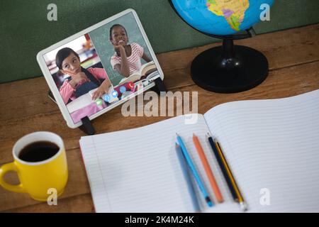 Smiling diverse elementary school pupils during class on tablet screen ...