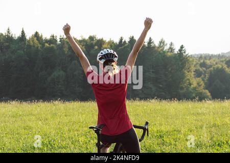 Female cycle race rider pedaling on an open road route in mountain ...