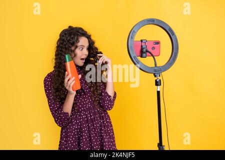 shocked teen girl presenting shampoo or hair body conditioner bottle ...
