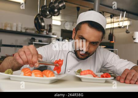 Sushi master prepares sushi for serving in modern commercial kitchen ...