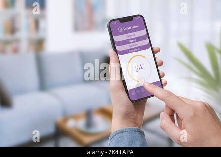 Woman setting home temperature using her smartphone, smart home ...