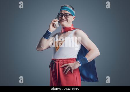 Funny confident superhero making a phone call using an old obsolete ...