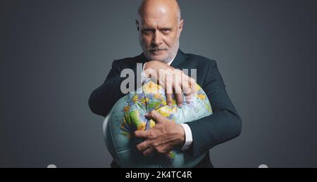 Greedy corporate businessman crushing a globe: earth exploitation and ...