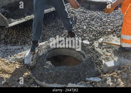 An installation of a cast iron sewer hatch in a concrete base for ...