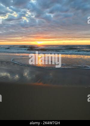 Vertical sunset shot over a sandy beach surrounded by mountains Stock ...