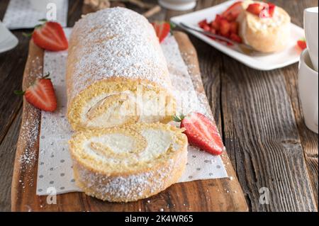 Baked biscuit swiss roll dessert with fruits and cream chopped on ...