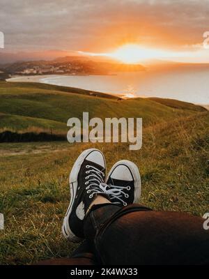crossed feet against orange sunset on beach landscape Stock Photo - Alamy