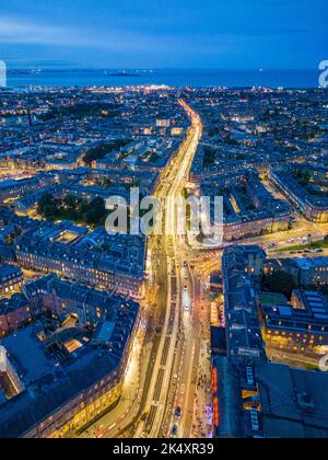 Night cityscape view from tram descending through forest and ...