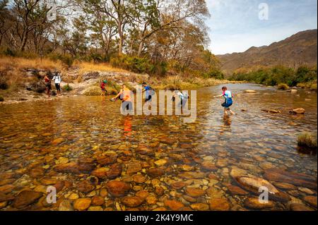 Tourists crossing the Mascates stream on the way to Bandeirinhas Canyon ...