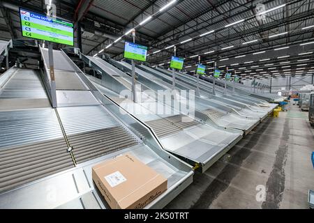 Postal parcels in a parcel sorting machine chute waiting to be sorted ...
