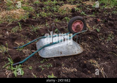 overturned wheelbarrow in the garden. wheelbarrow lying on the ground ...