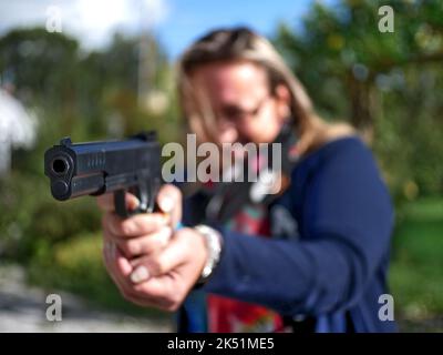 gun held by a blurry caucasian man, outdoor Stock Photo - Alamy
