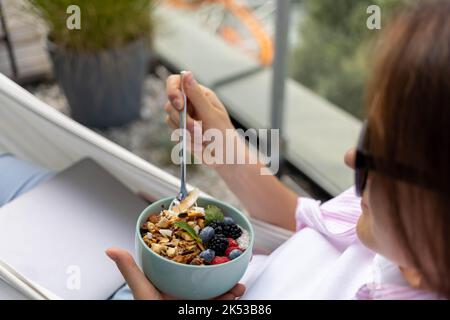 young woman eating chia pudding with nuts and berries Stock Photo - Alamy