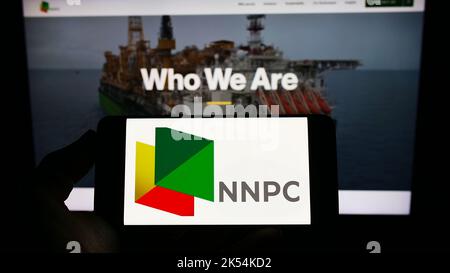 Person holding smartphone with logo of Nigerian National Petroleum ...