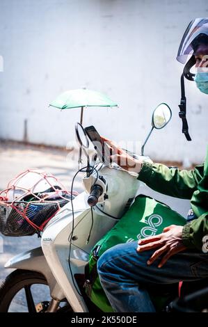 A Grab bike courier arrives to pick up a parcel in Bangkok Thailand ...