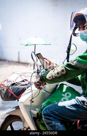 A Grab bike courier arrives to pick up a parcel in Bangkok Thailand ...