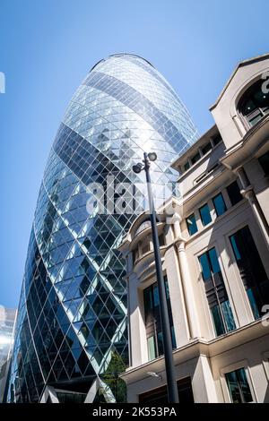 The glass Gherkin Building looms up and shines bright from the street ...