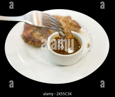 Die cut of grilled pork chop with knife and fork, on black isolated ...