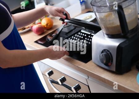 Woman opens waffle iron to make waffles in kitchen Stock Photo - Alamy
