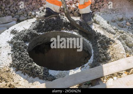 Cast iron sewer hatch being installed on a concrete base as part of the ...