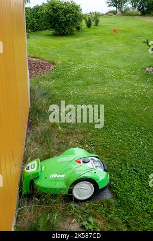 Lawn mower autonomous robot in grass field outdoors on a charging ...