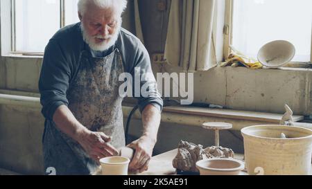 Experienced male potter is mixing and kneading clay while his cute ...