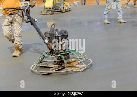 Worker levels fresh concrete with trowel on wooden frame at ...