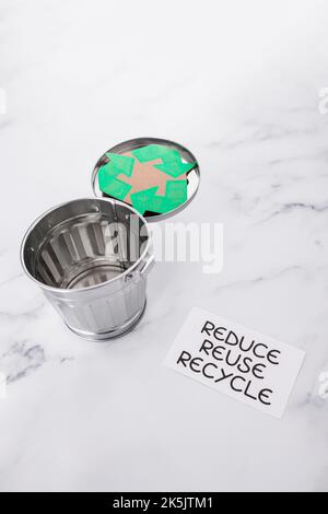 reduce reuse recycle sign with mini trash can next to recycle icon ...