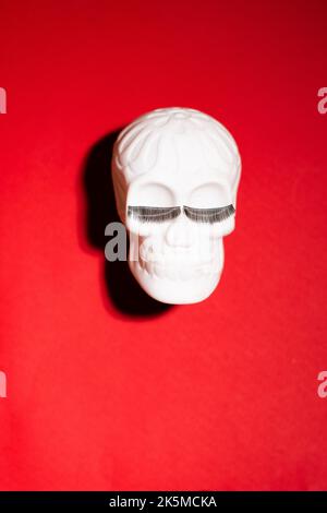 Cheerful Human skull with eyelashes on a red background Stock Photo - Alamy