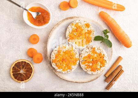 Carrot jam with puffed rice cakes on gray concrete background. Top view ...