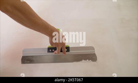Worker spackles the walls with a spatula. Spatula with putty in hand ...
