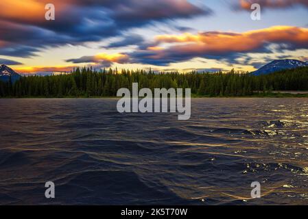 Colorful sunset over a calm lake with reflections in the water and ...