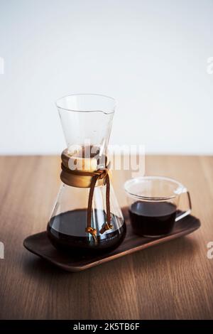 A vertical shot of a wooden coffee drip set with mugs on a table ...