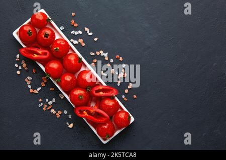 Fresh washed cherry tomatoes and paprika slices on a white oblong dish ...