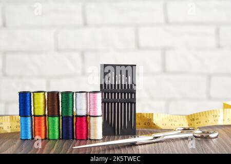 Thread spools, needles and measuring tape on light blue background ...