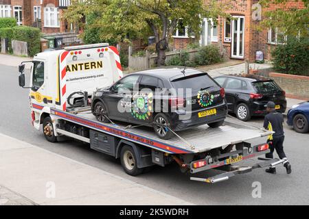 break-down zipcar car is hoisted onto a loading ramp and secured on a ...