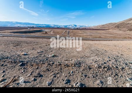 An asphalt road stretches across a vast active solid-waste landfill ...