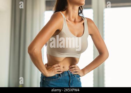 Unrecognizable young lady doing stomach vacuum exercise, flexing ...