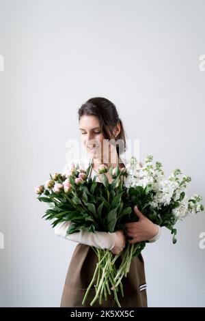 WOMAN florist EMBRACING a bunch of white and pink flowers on white ...