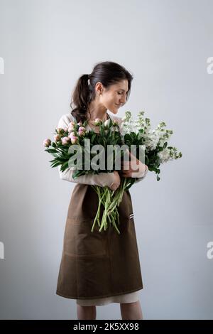 WOMAN florist EMBRACING a bunch of white and pink flowers on white ...