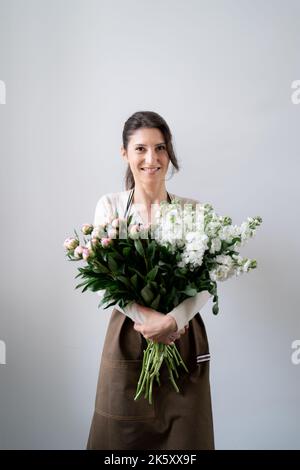 WOMAN florist EMBRACING a bunch of white and pink flowers on white ...
