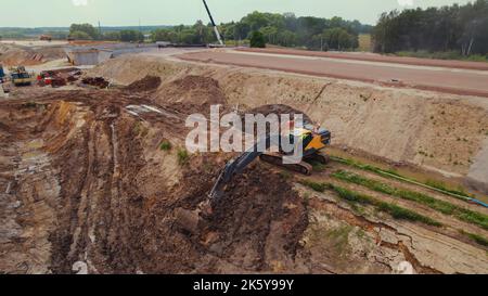 An earthmoving worker digging ground at construction site with crawler ...