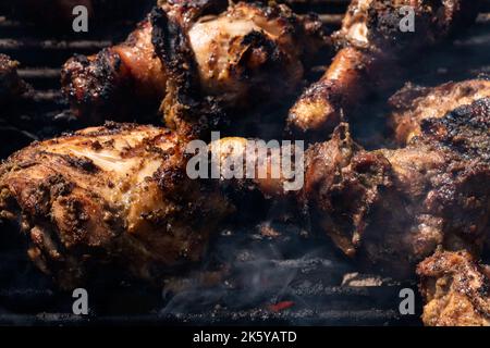 Grilling traditional Jamaican spicy jerk chicken with over charcoal ...