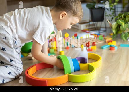 Funny baby boy playing multicolored arch Montessori wooden material ...