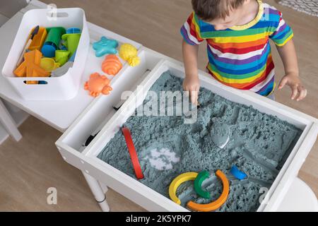 Overjoyed male kid playing kinetic sand early development education ...