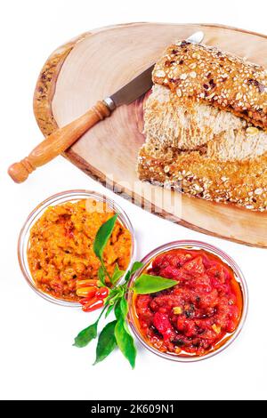 Balkan meze consisting of two types of red pepper spread, bread ...