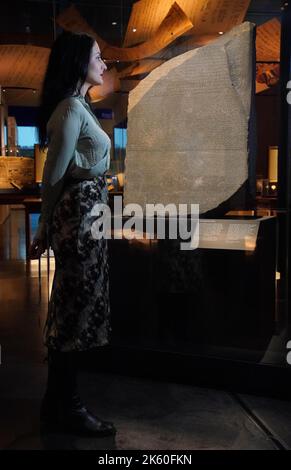 A member of staff observes the Rosetta Stone on display during the ...