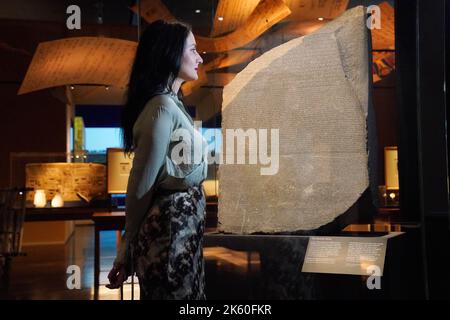 A member of staff observes the Rosetta Stone on display during the ...