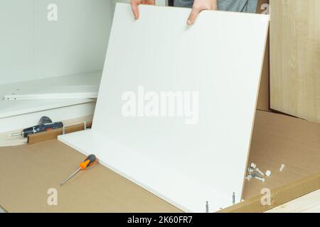 Male hands hold and insert bottom of white drawer, assembling dresser ...